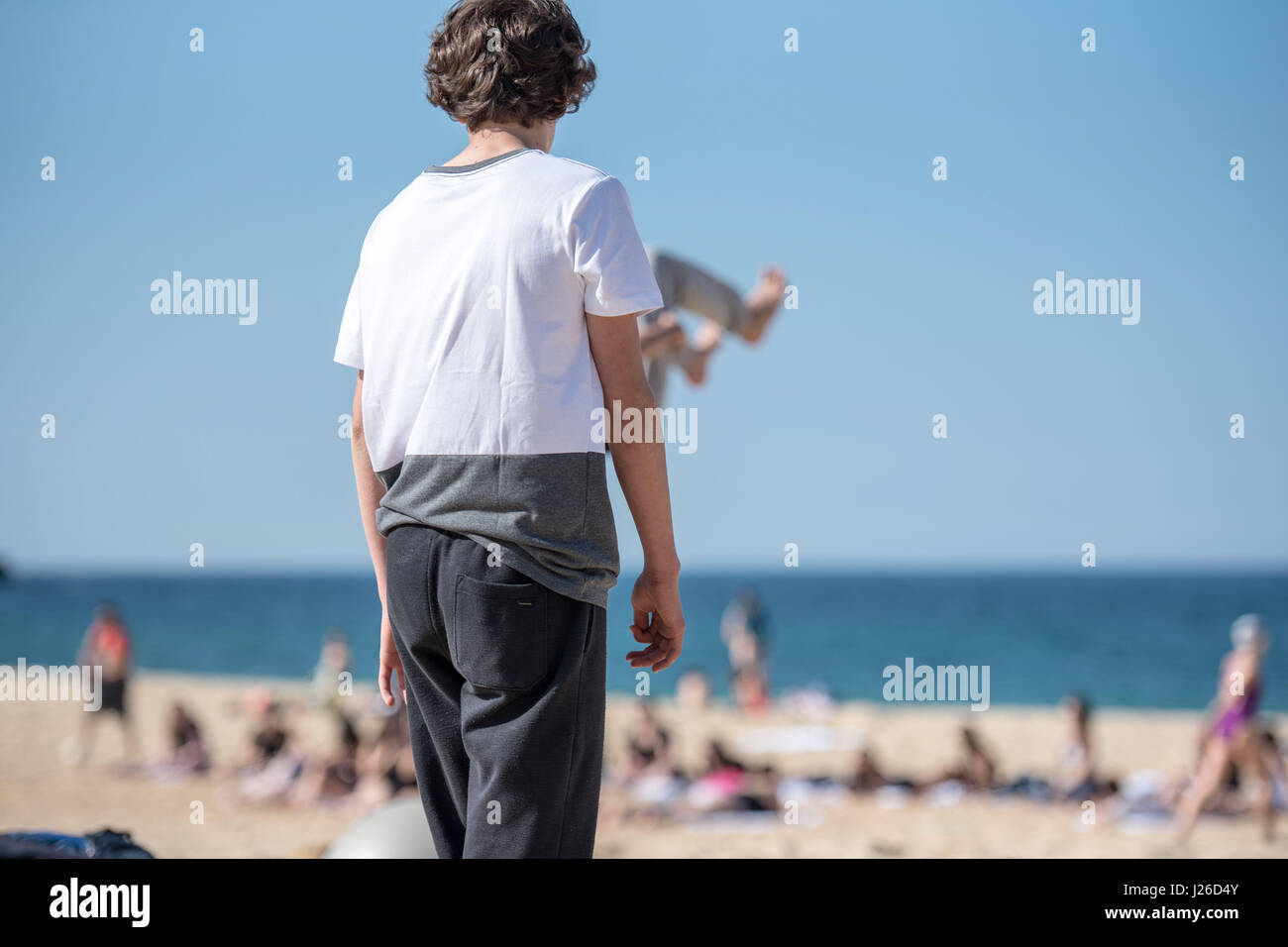 Kids are jumping very high on a beach and doing flip overs turning in ...