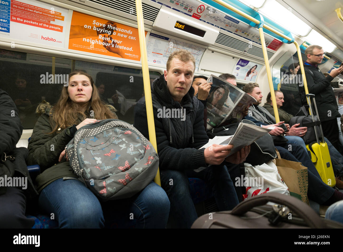 Passengers reading newspapers in a London Underground tube train ...