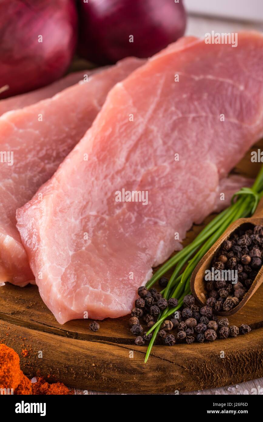 Vertical photo of three slices of raw pork meat which are placed on ...