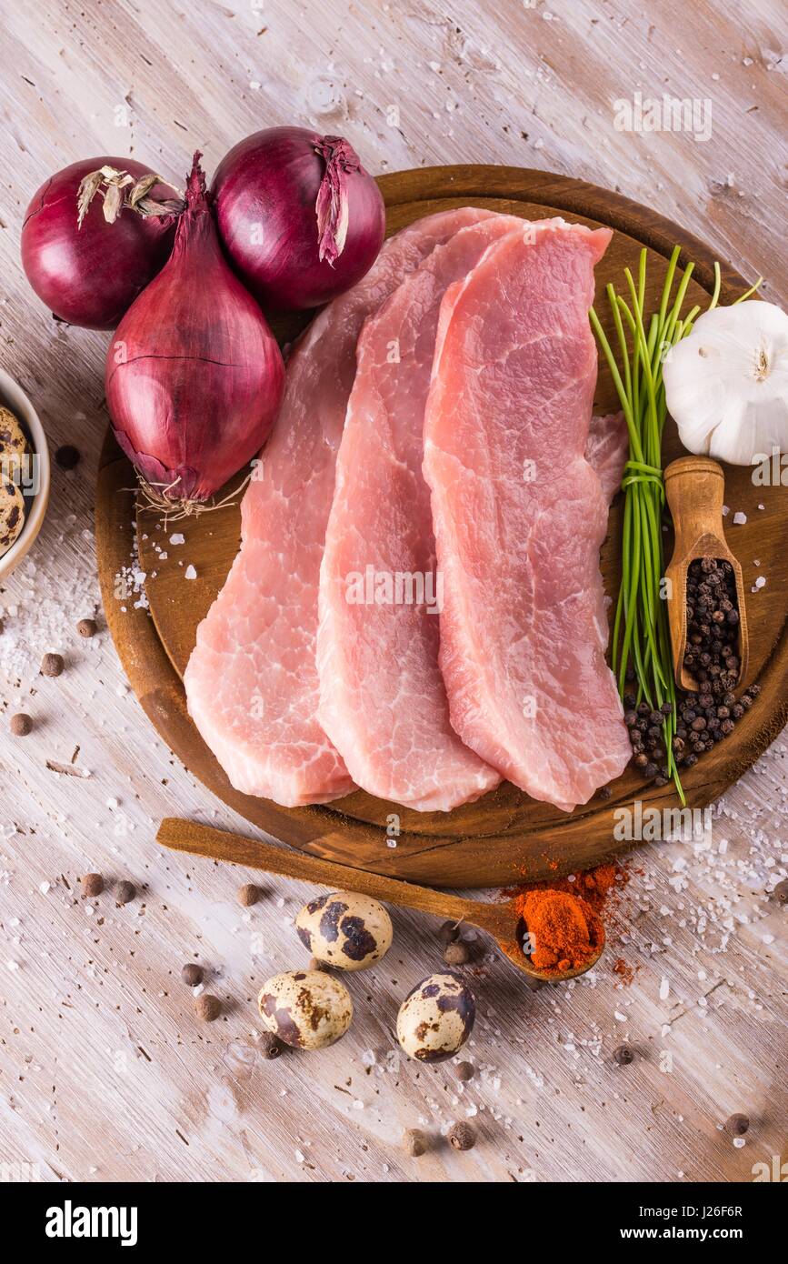 Vertical photo of three slices of raw pork meat which are placed on ...