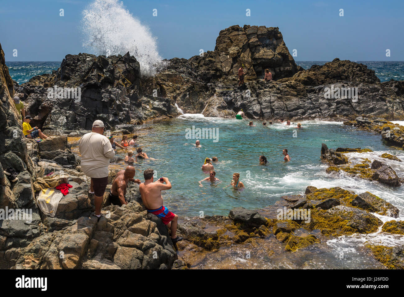 A wave explodes over the walls of the Conchi Natural Pool, Aruba Stock ...