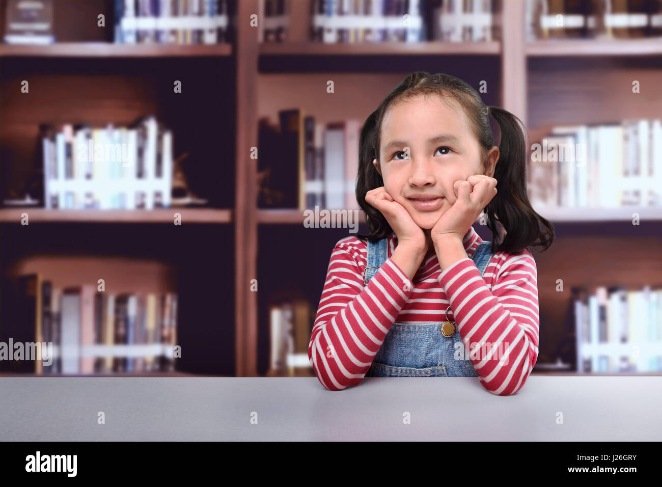 Cheerful asian kid thinking for new idea in the library Stock Photo - Alamy