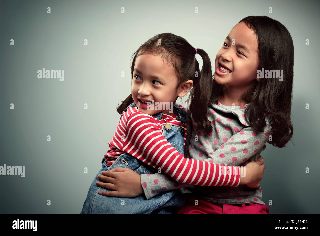 Portrait of two asian little kids with scared expression over grey ...