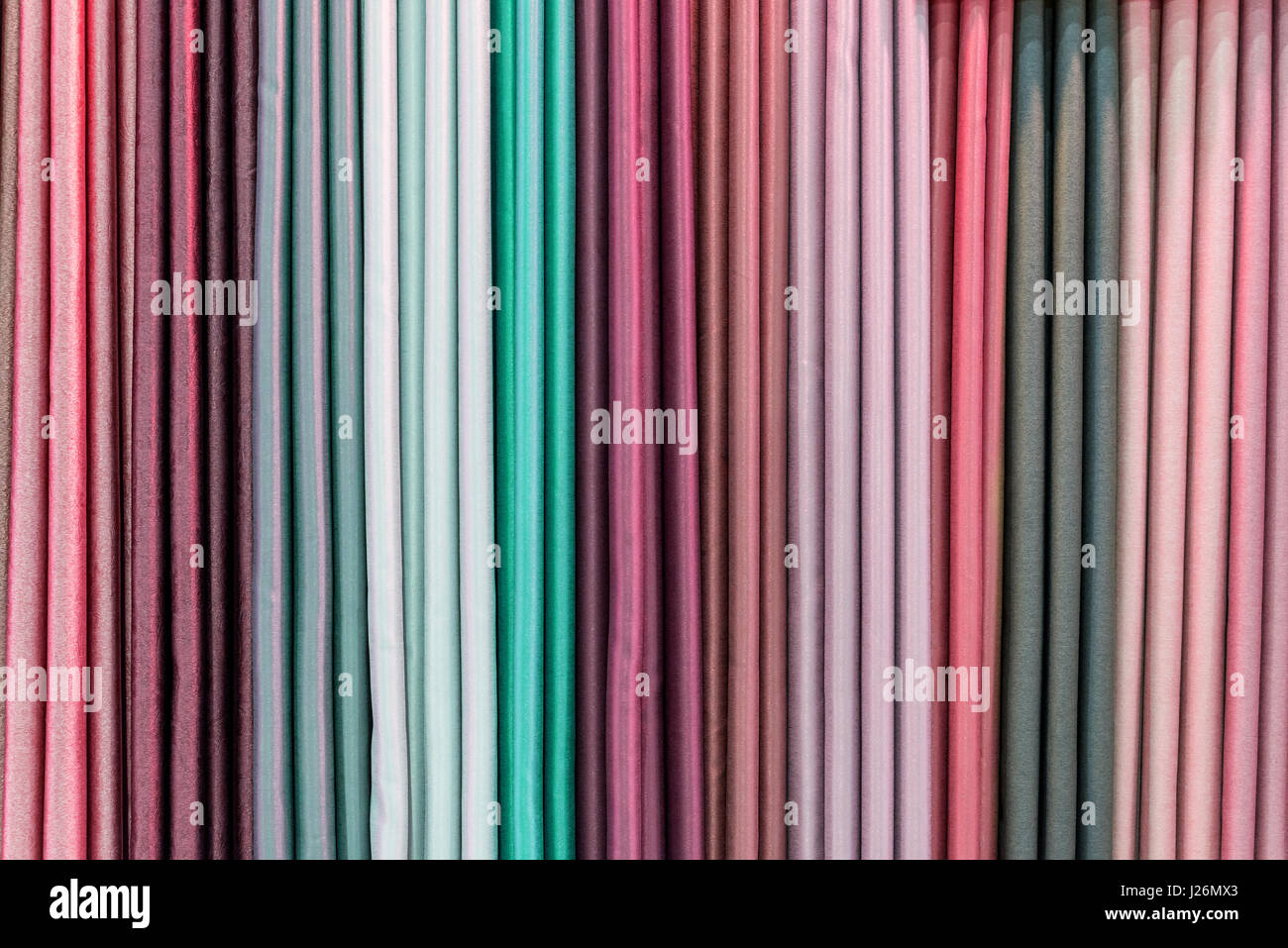 Colorful curtain samples hanging from hangers on a rail in a display in ...