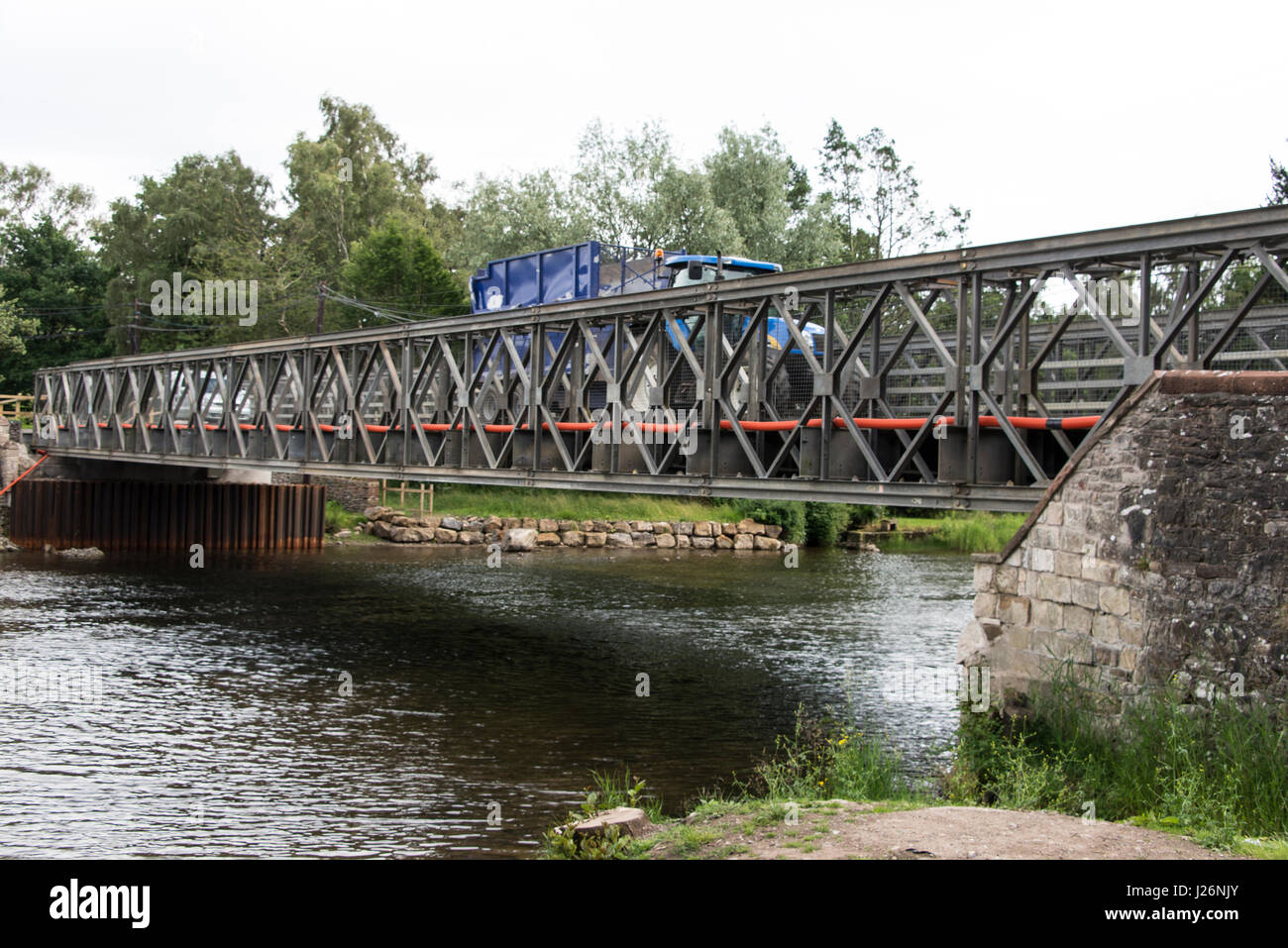 A temporary metal bridge with a green pedestrian walkway at Pooley ...