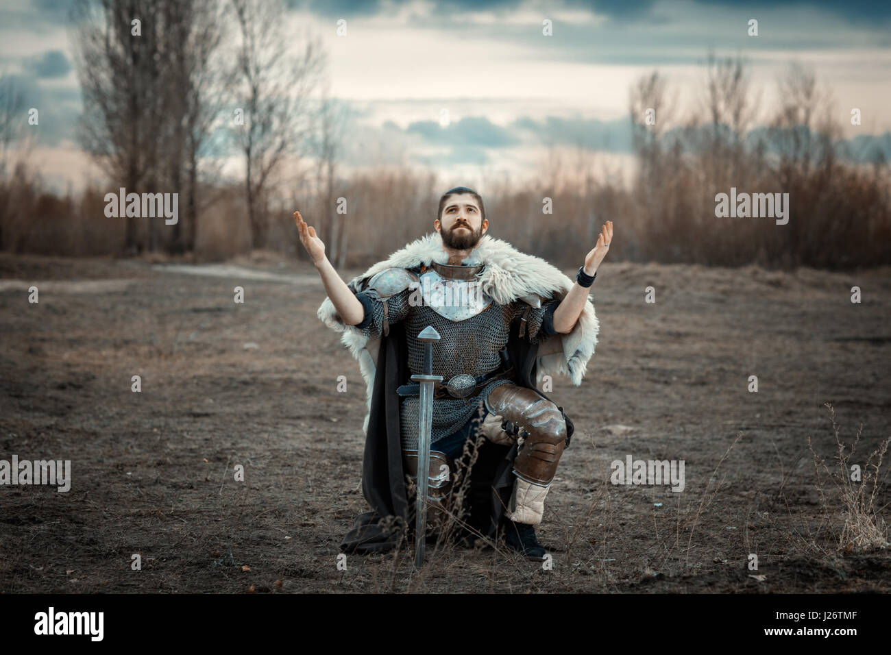 Warrior stood on one knee in the field and raised his hands to the sky ...