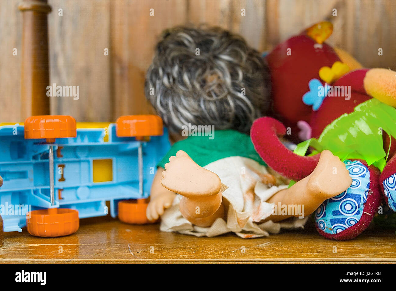 Dolls and a tipped over toy truck on the wooden shelf, focus in the ...