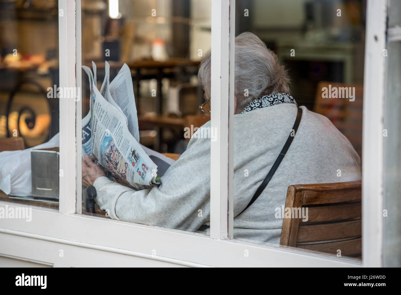 Old lady reading newspaper in cafe Stock Photo - Alamy