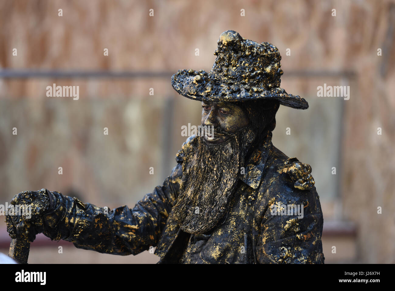 Street artist dressed as a gold statue collects money for living Stock ...