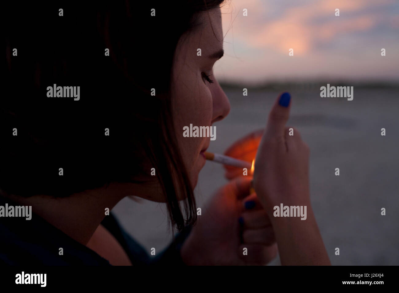 Young woman lighting a cigarette Stock Photo - Alamy