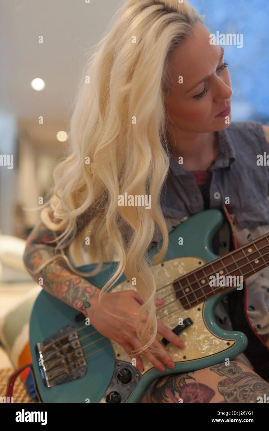 Beautiful young woman playing an electric bass guitar Stock Photo - Alamy