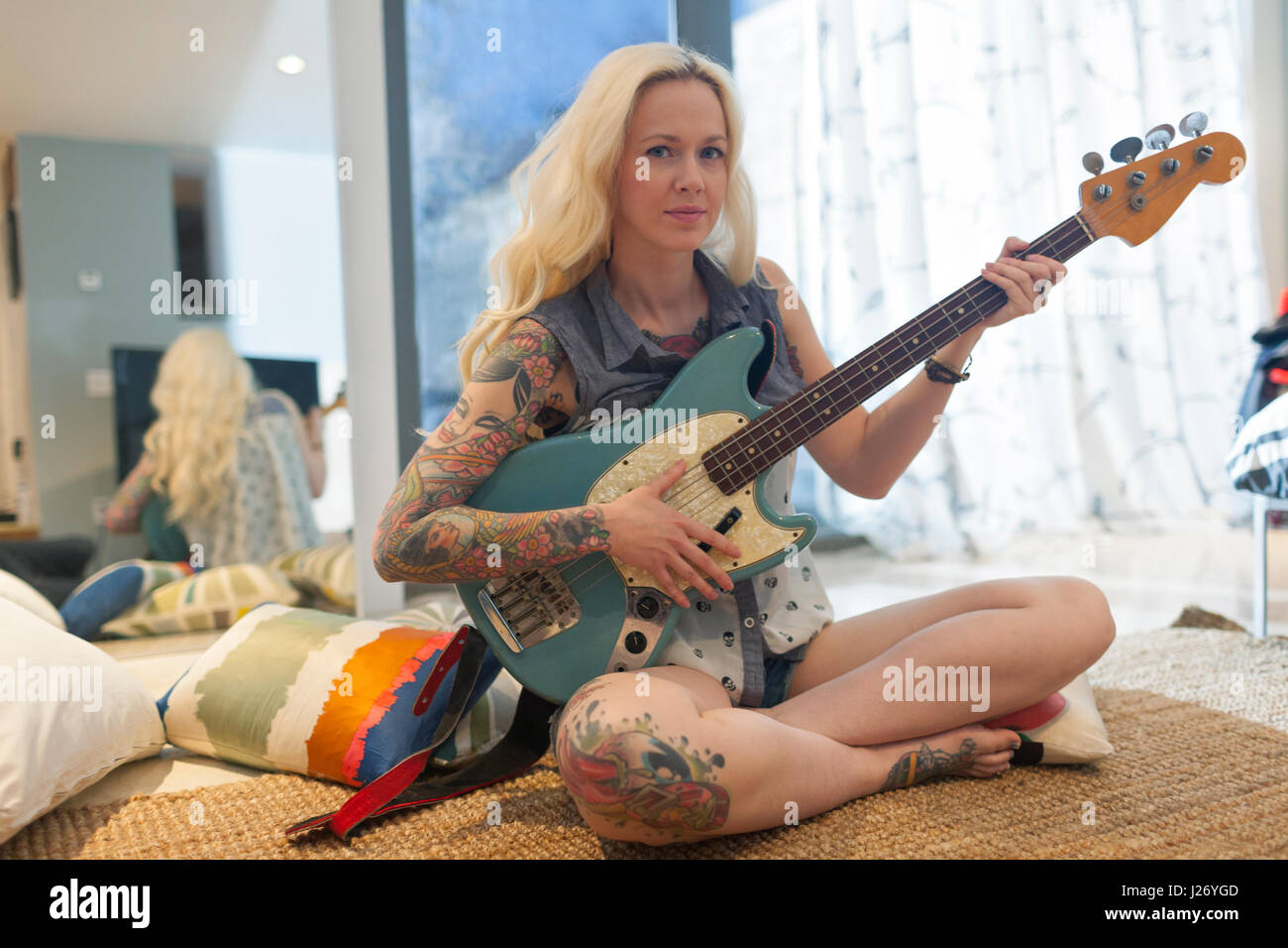 Beautiful young woman playing an electric bass guitar Stock Photo - Alamy