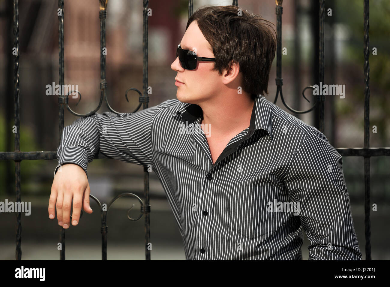 Young man at the cast iron fence Stock Photo - Alamy