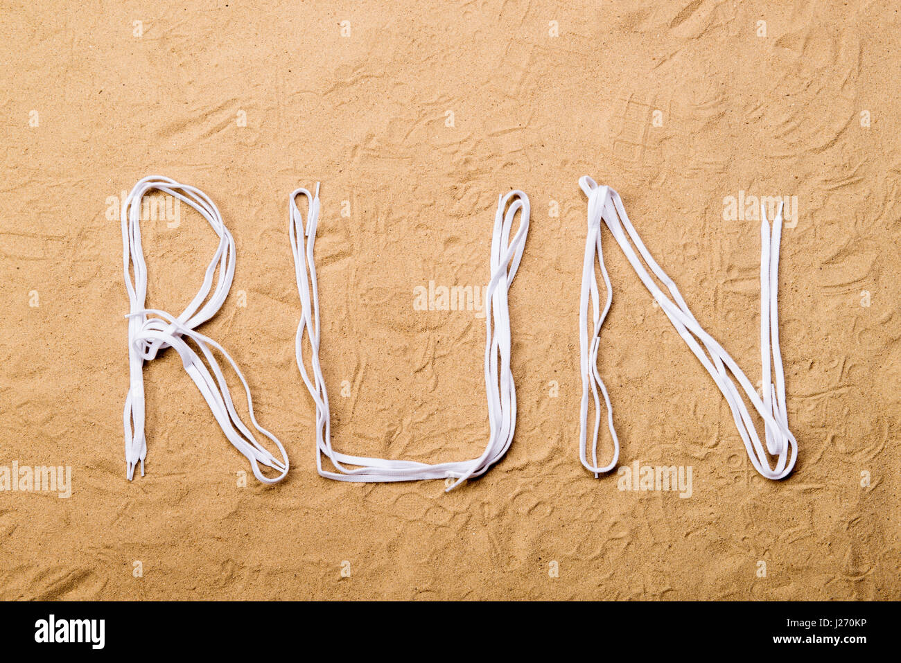Run sign made of shoelaces, sand background. Flat lay Stock Photo - Alamy