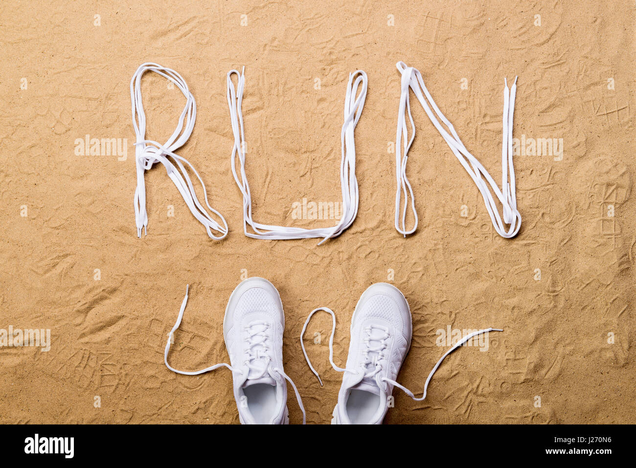 Running shoes and run sign made of shoelaces, sand Stock Photo - Alamy