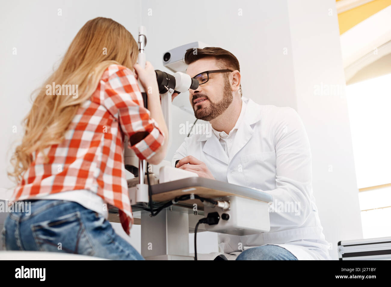 Concentrated diligent ophthalmologist observing patients eyes Stock ...