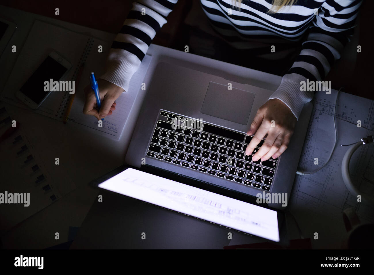 Unrecognizable woman sitting at desk working on laptop Stock Photo - Alamy