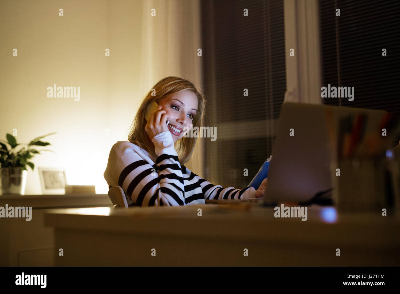 Woman with laptop and smartphone, making phone call Stock Photo - Alamy