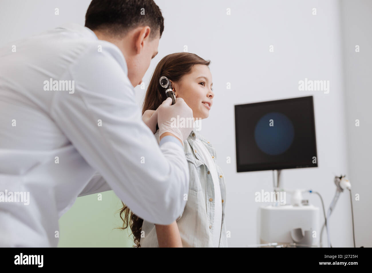Use otoscope. Funny brunette girl standing in semi position keeping her ...
