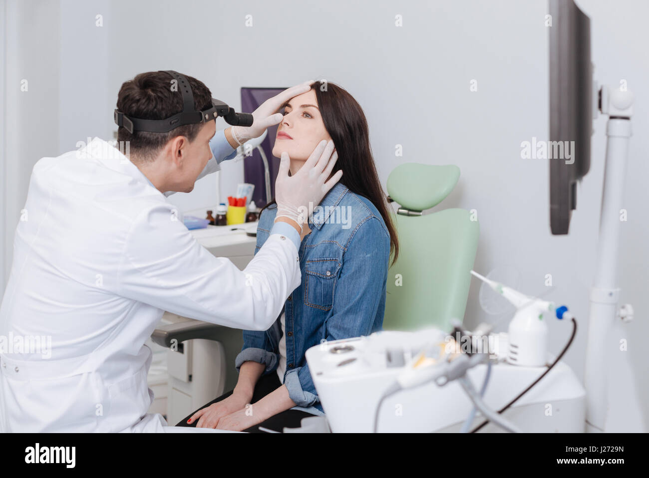 Very attentive medical worker looking at nose of his visitor Stock ...