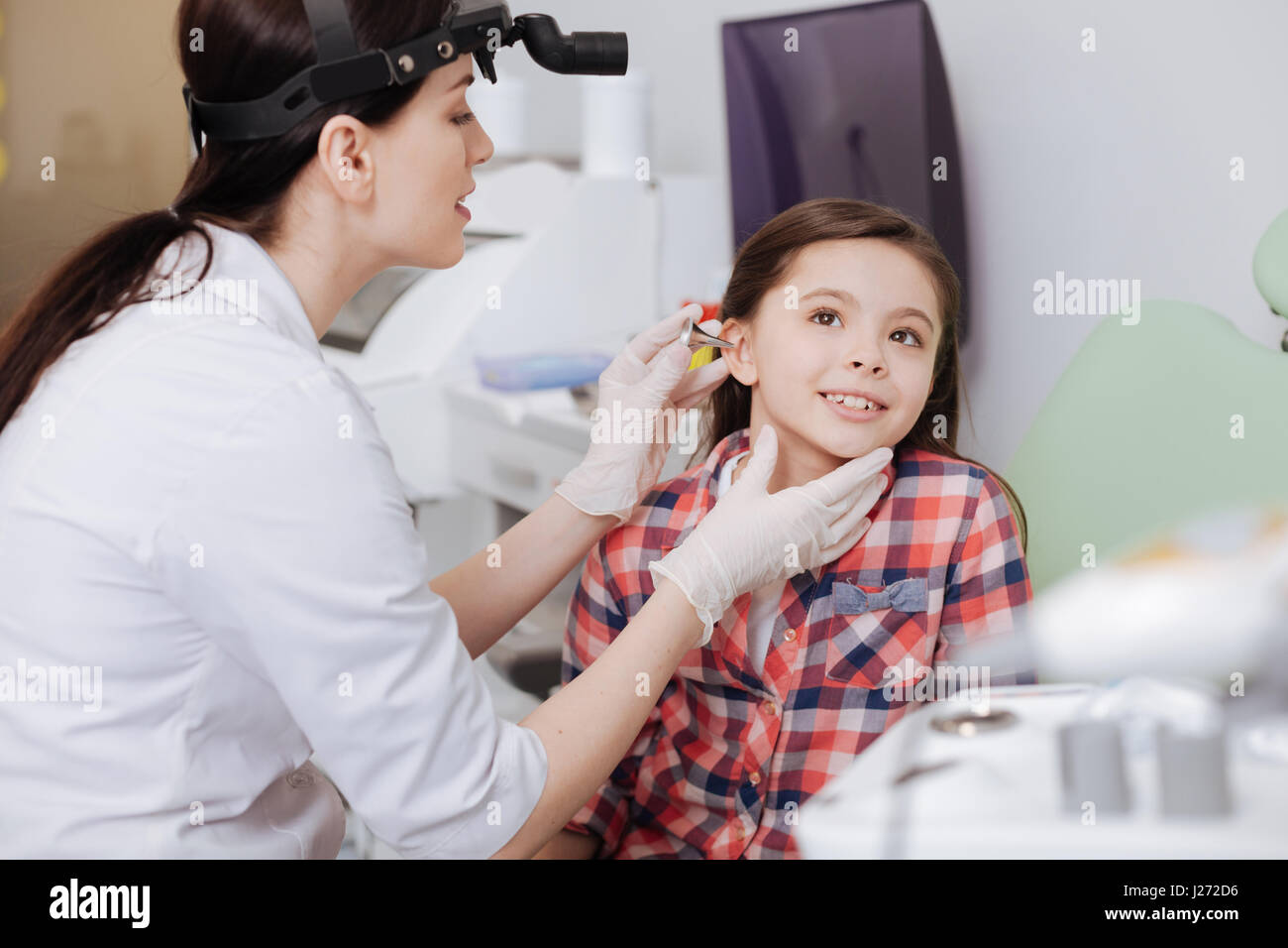 Attentive doctor putting ear-funnel into ear of her patient Stock Photo ...