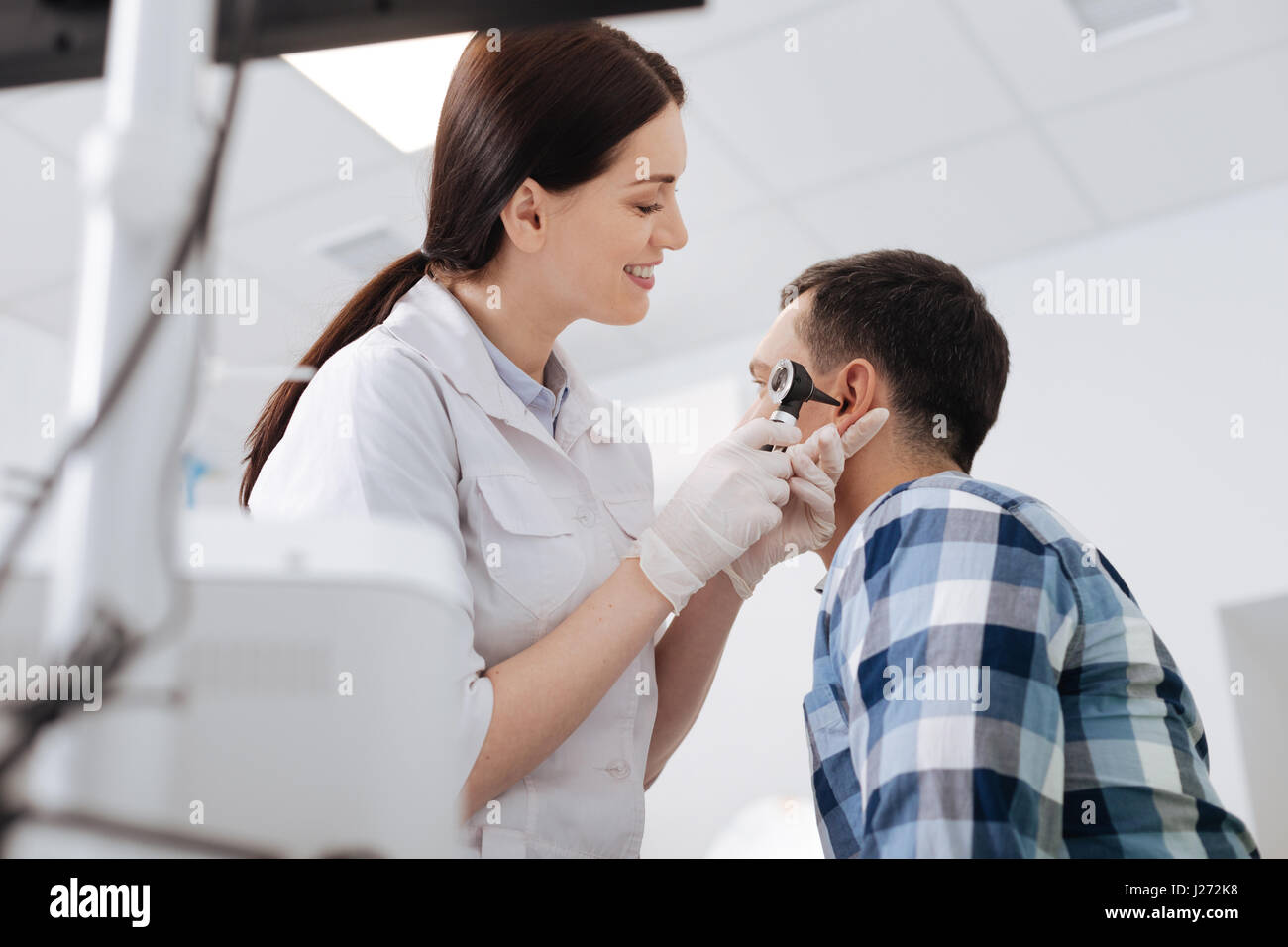 Profile photo of otolaryngologist holding otoscope near ear of patient ...