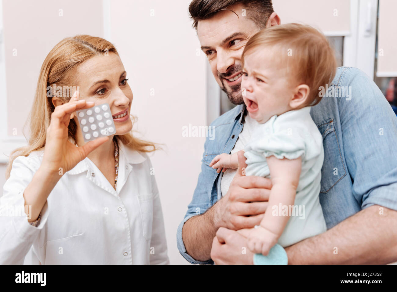 Crying baby girl looking at plate with tablets Stock Photo - Alamy