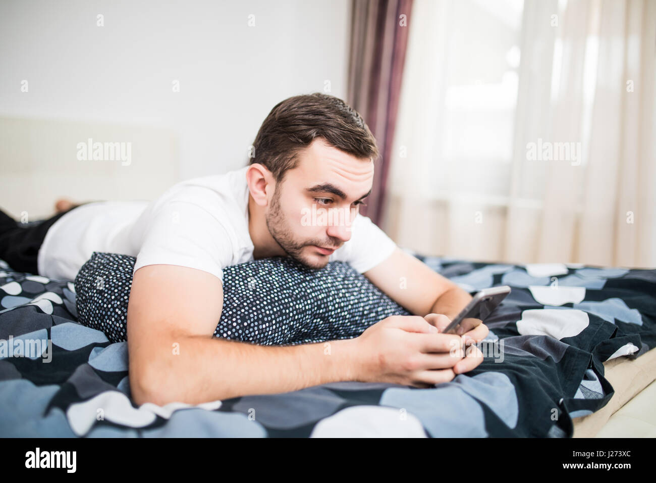 young cell phone addict man awake at night in bed using smartphone for ...