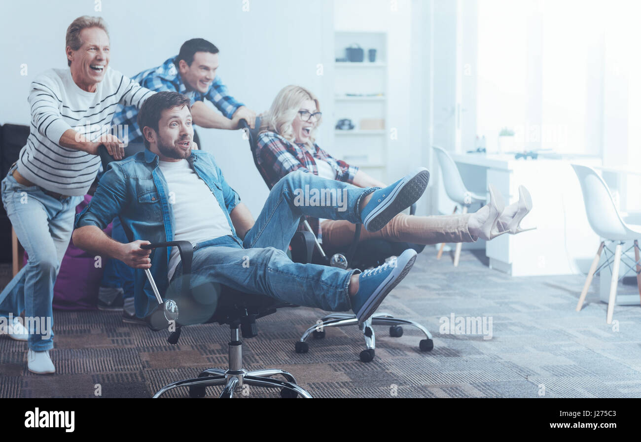 Office workers having fun with a swivel chair Stock Photo - Alamy
