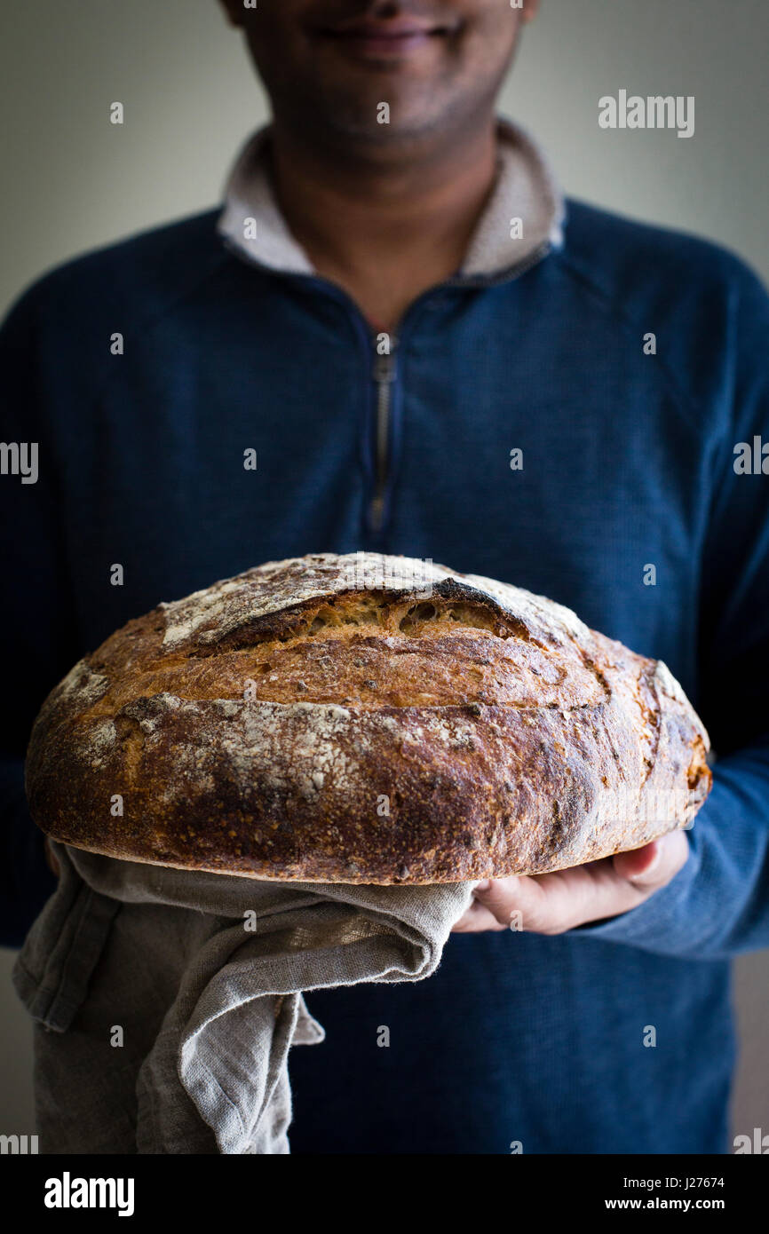 Man holding freshly baked sourdough bread front view Stock Photo - Alamy