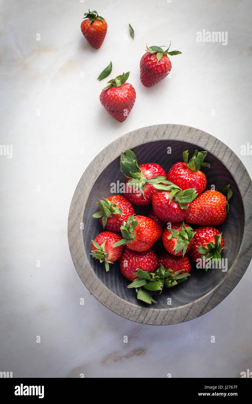 Strawberries in a grey wooden bowl on a marble table on top view Stock ...