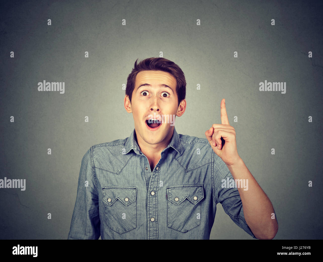 Young man has idea, pointing with finger up isolated on gray background ...