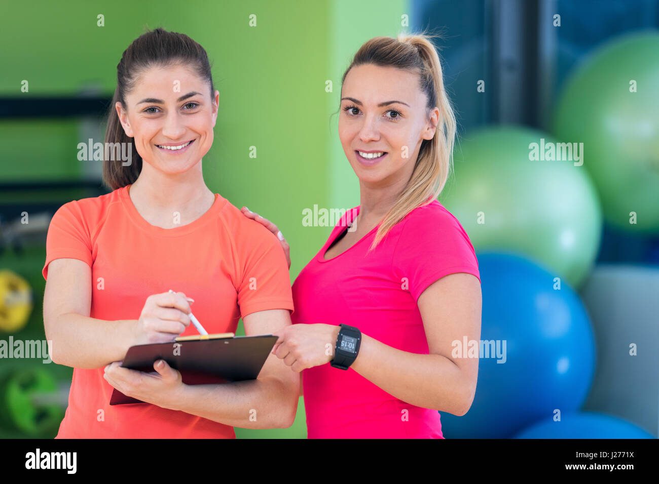 Two young woman enjoying their exercise routine at the gym laughing and ...