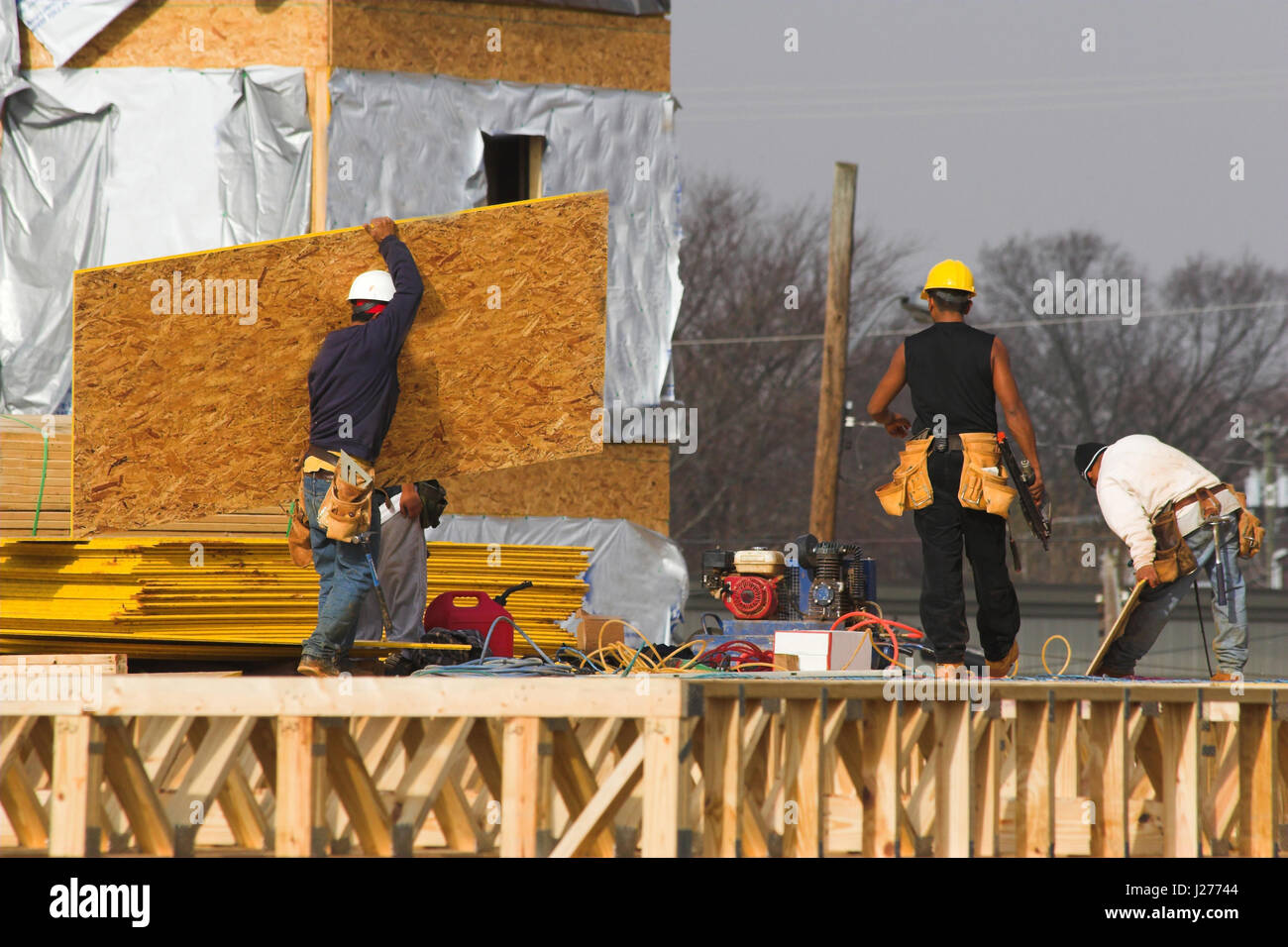Carpenters Cutting And Installing Framework And Subflooring On Second Story Of New Apartment