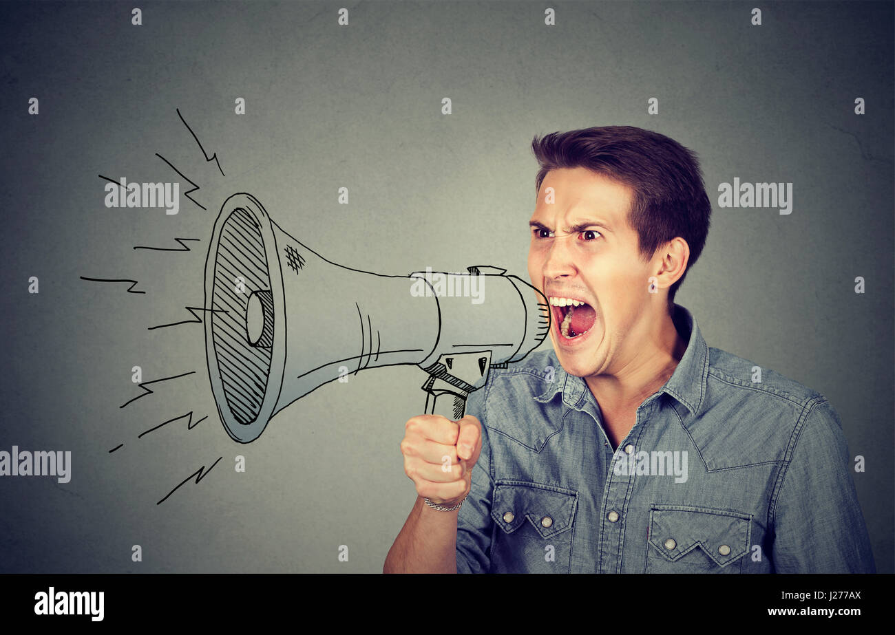 Side portrait angry young man holding screaming in megaphone isolated ...