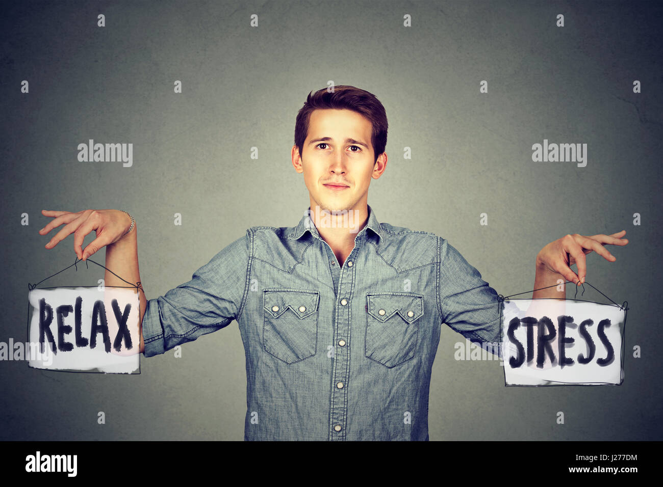 Stress or relax. Young man holding two signs isolated on gray ...
