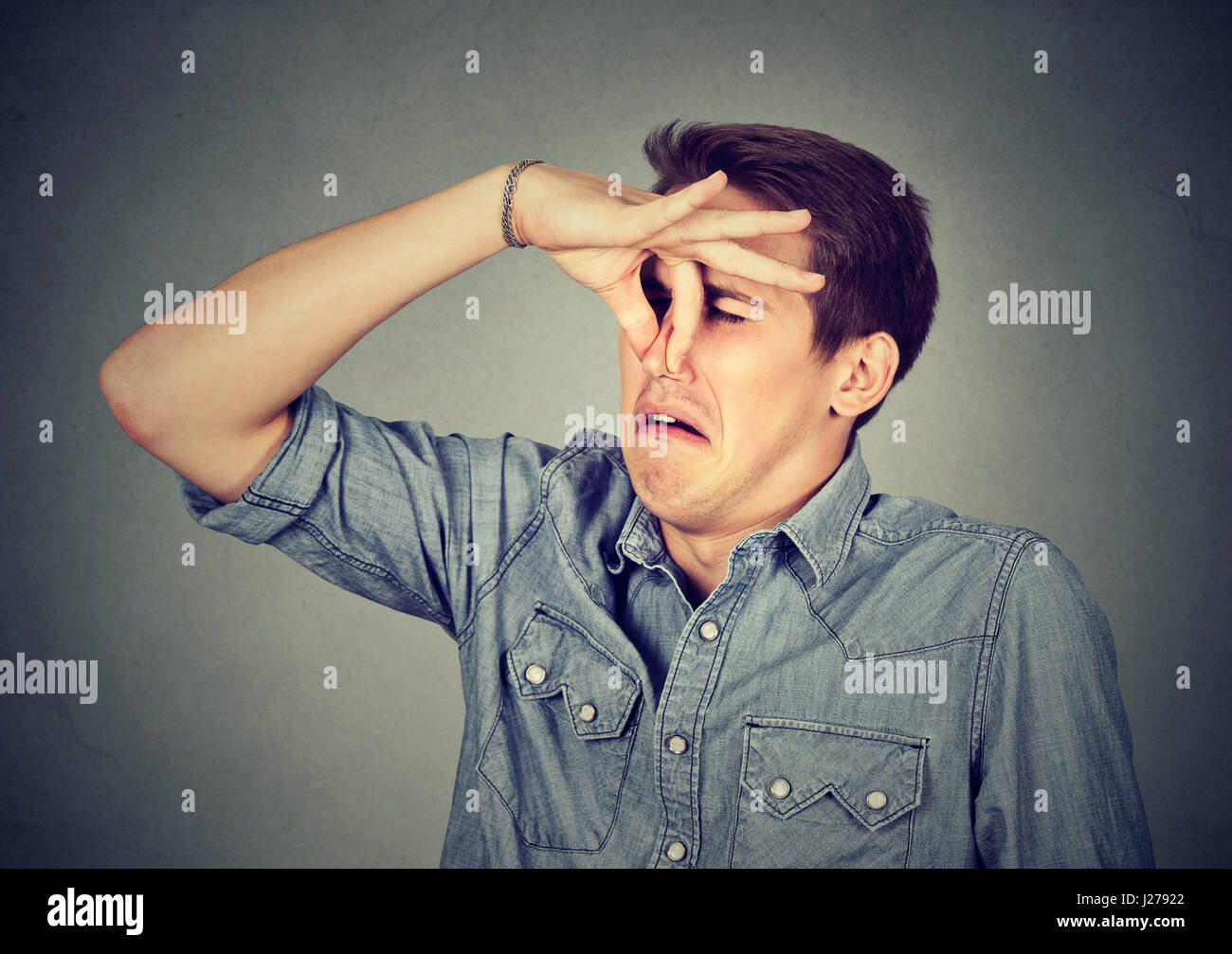 man pinches nose with fingers looks with disgust something stinks bad ...