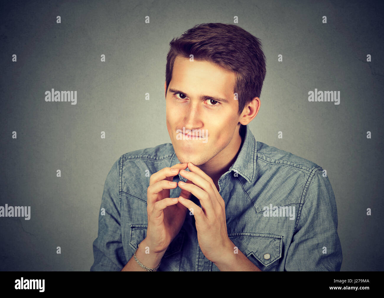 Sneaky scheming young man plotting something isolated on gray wall ...