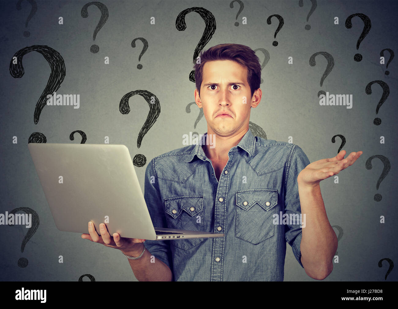 Perplexed young man with laptop many questions and no answer Stock ...