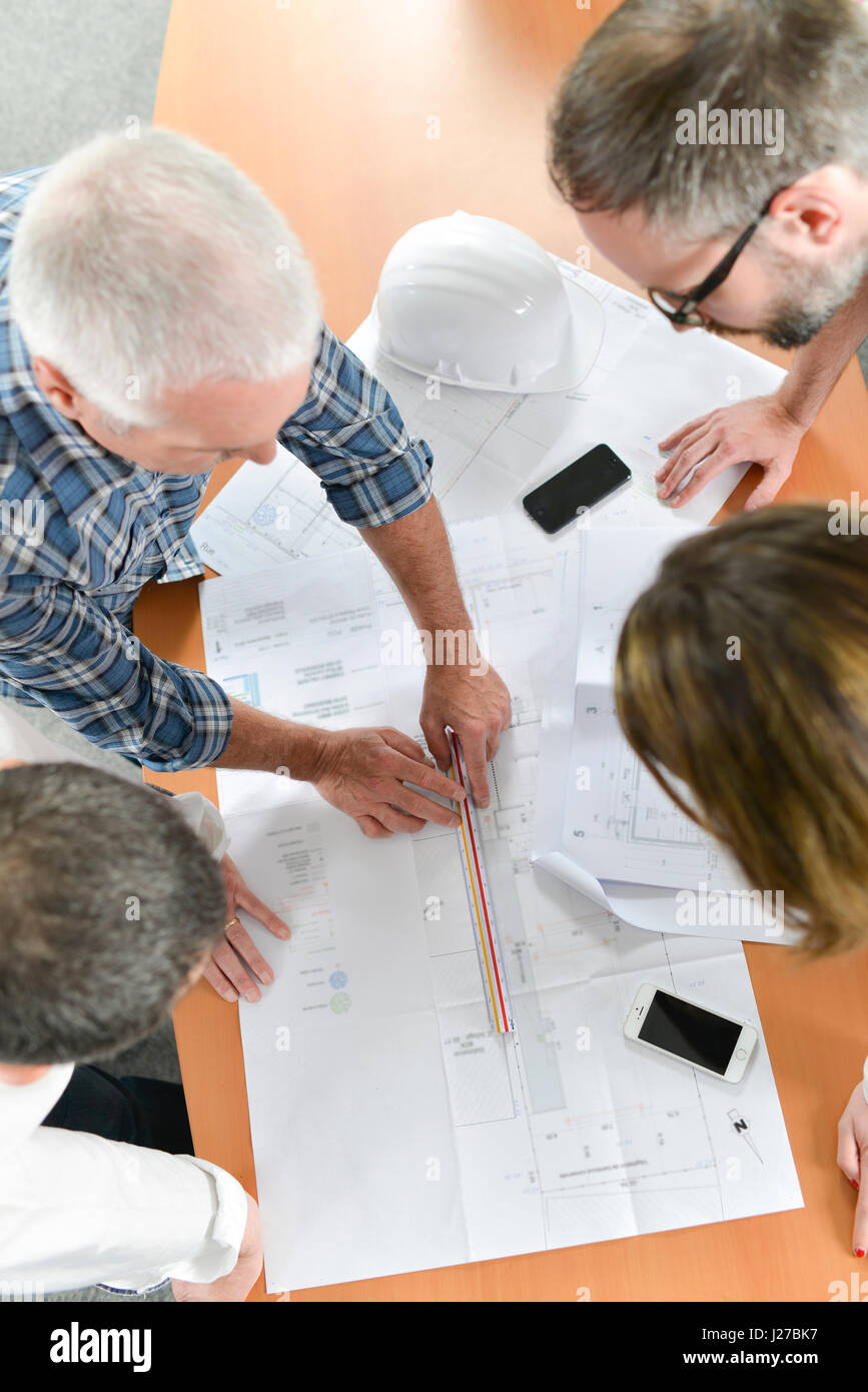 Downward view of men looking at blueprints Stock Photo - Alamy