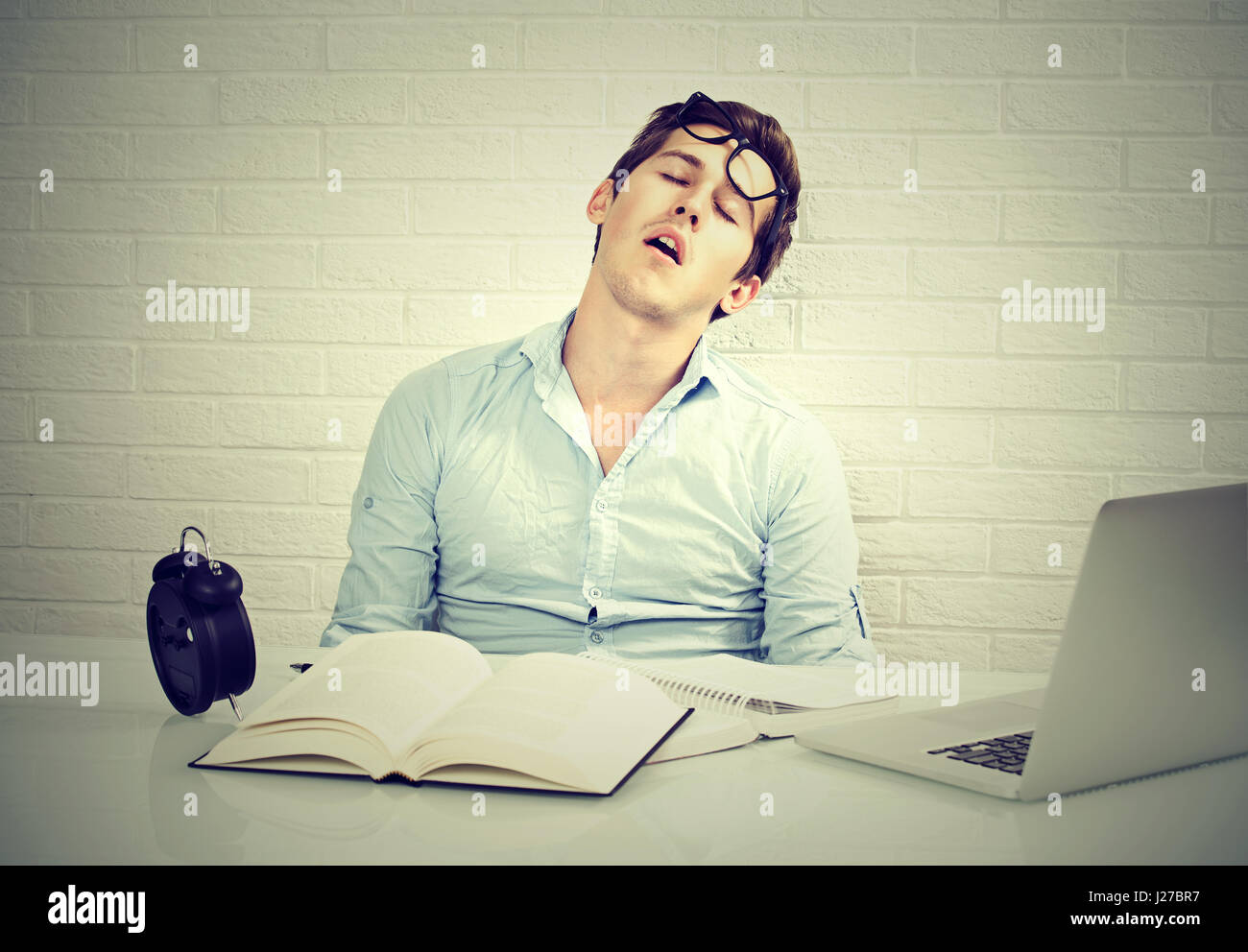 Too much work tired sleepy young man sitting at desk with books in ...