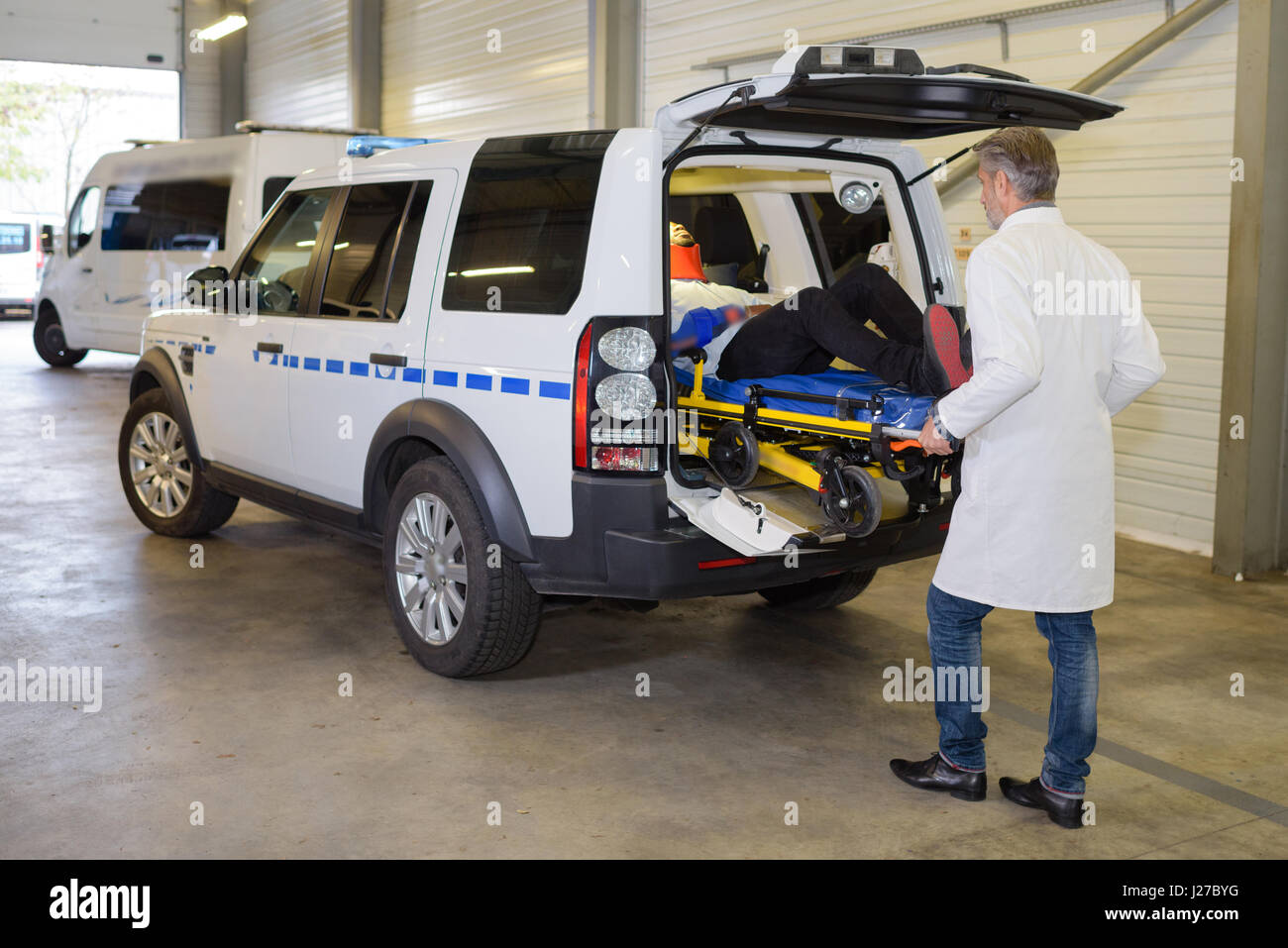 Paramedic loading stretcher into ambulance vehicle Stock Photo - Alamy