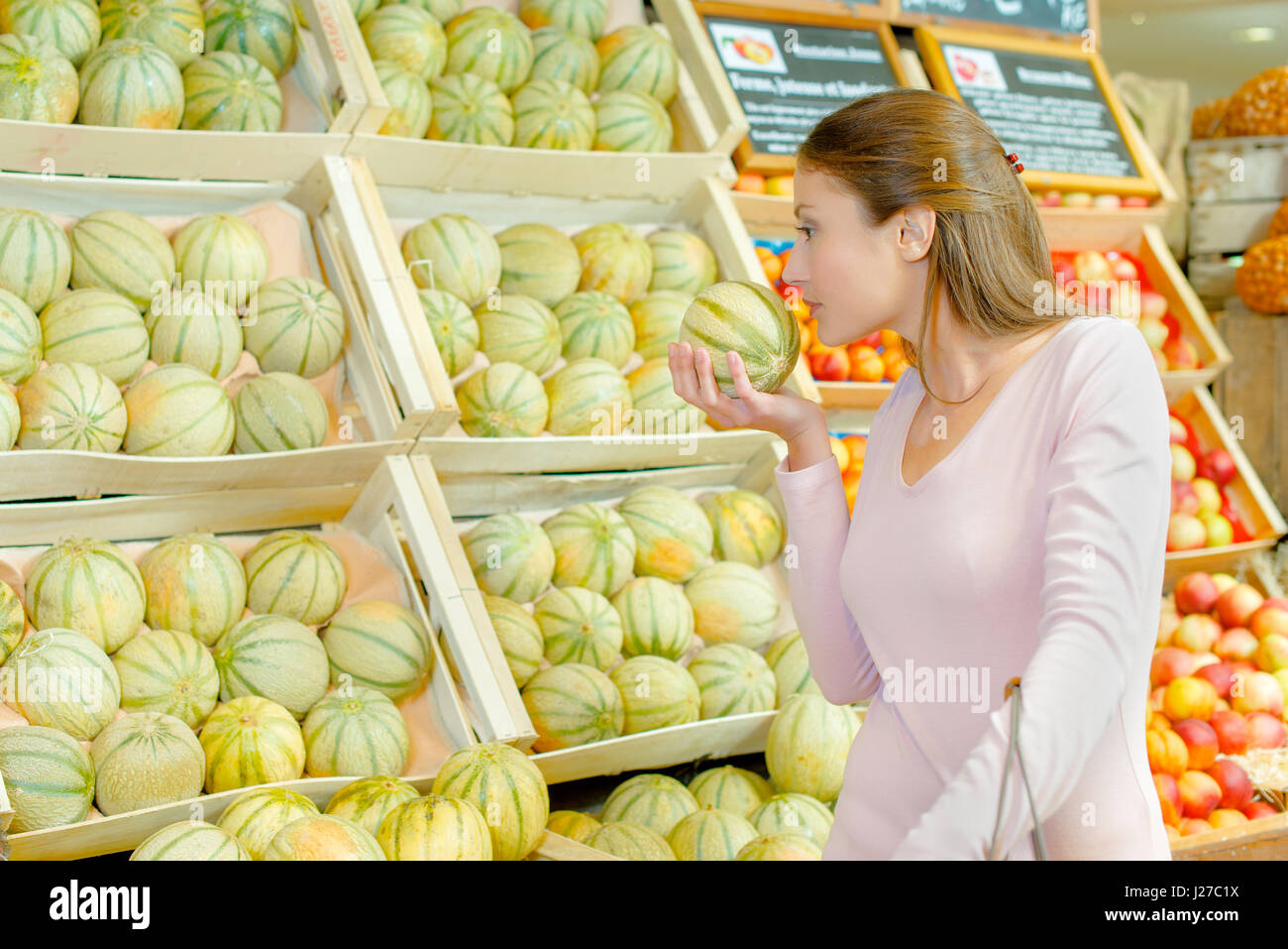 Lady smelling melon in grocers Stock Photo - Alamy