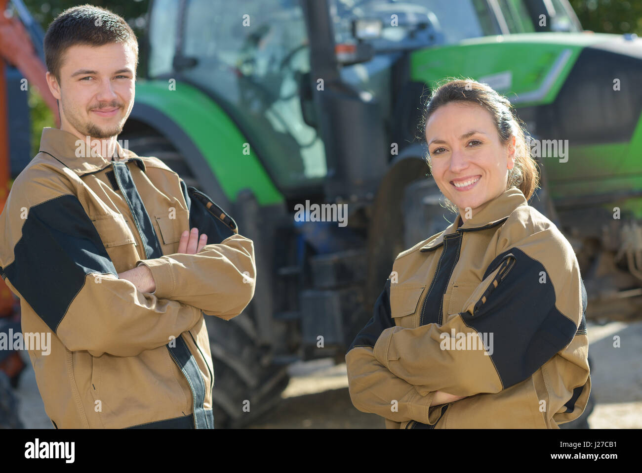 couple standing in front of tractor Stock Photo - Alamy