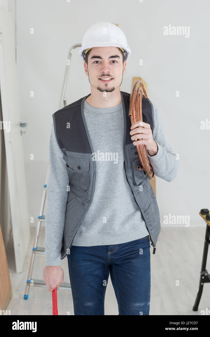 Portrait of man carrying copper pipe Stock Photo - Alamy