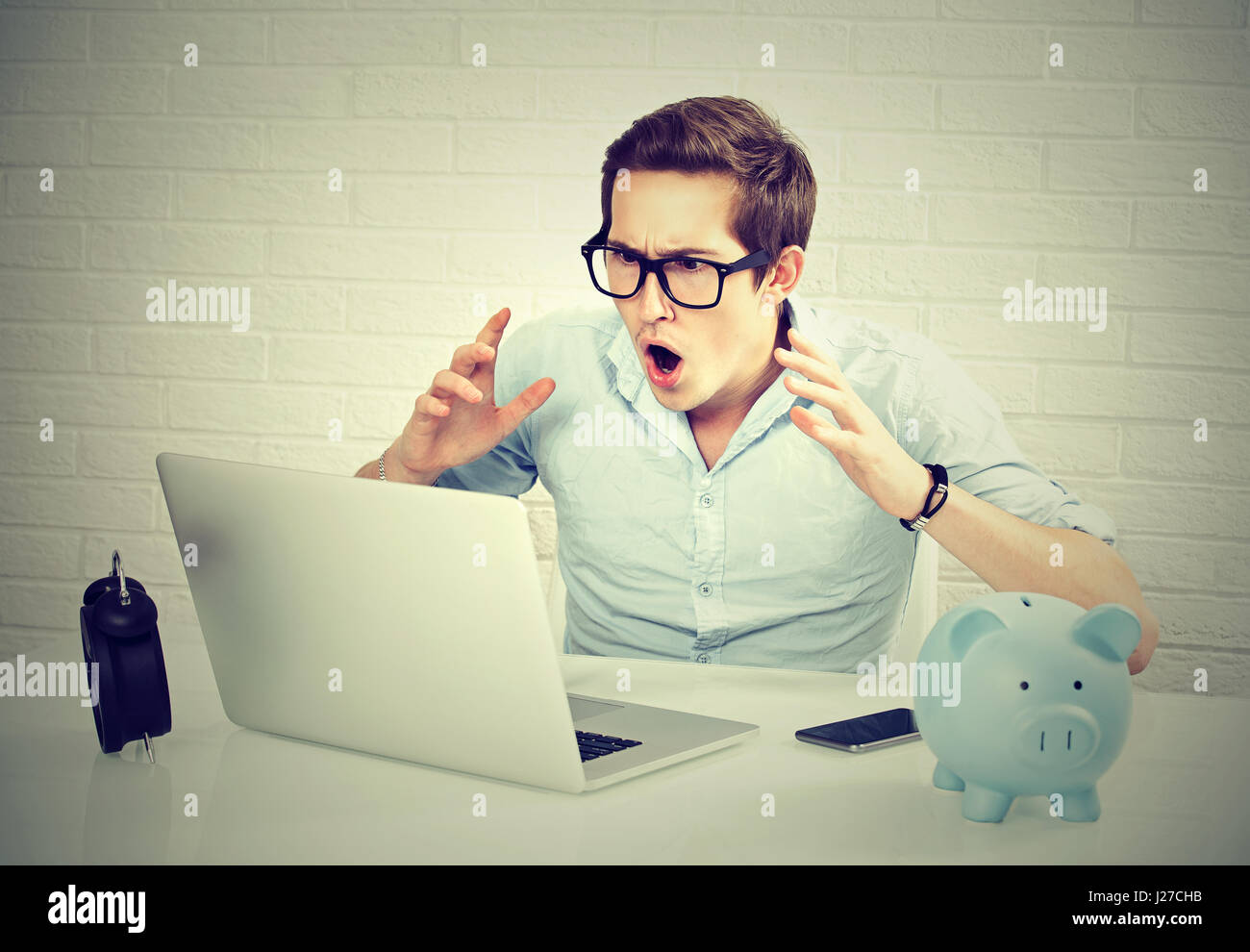 shocked man looking at laptop computer sitting at table Stock Photo - Alamy