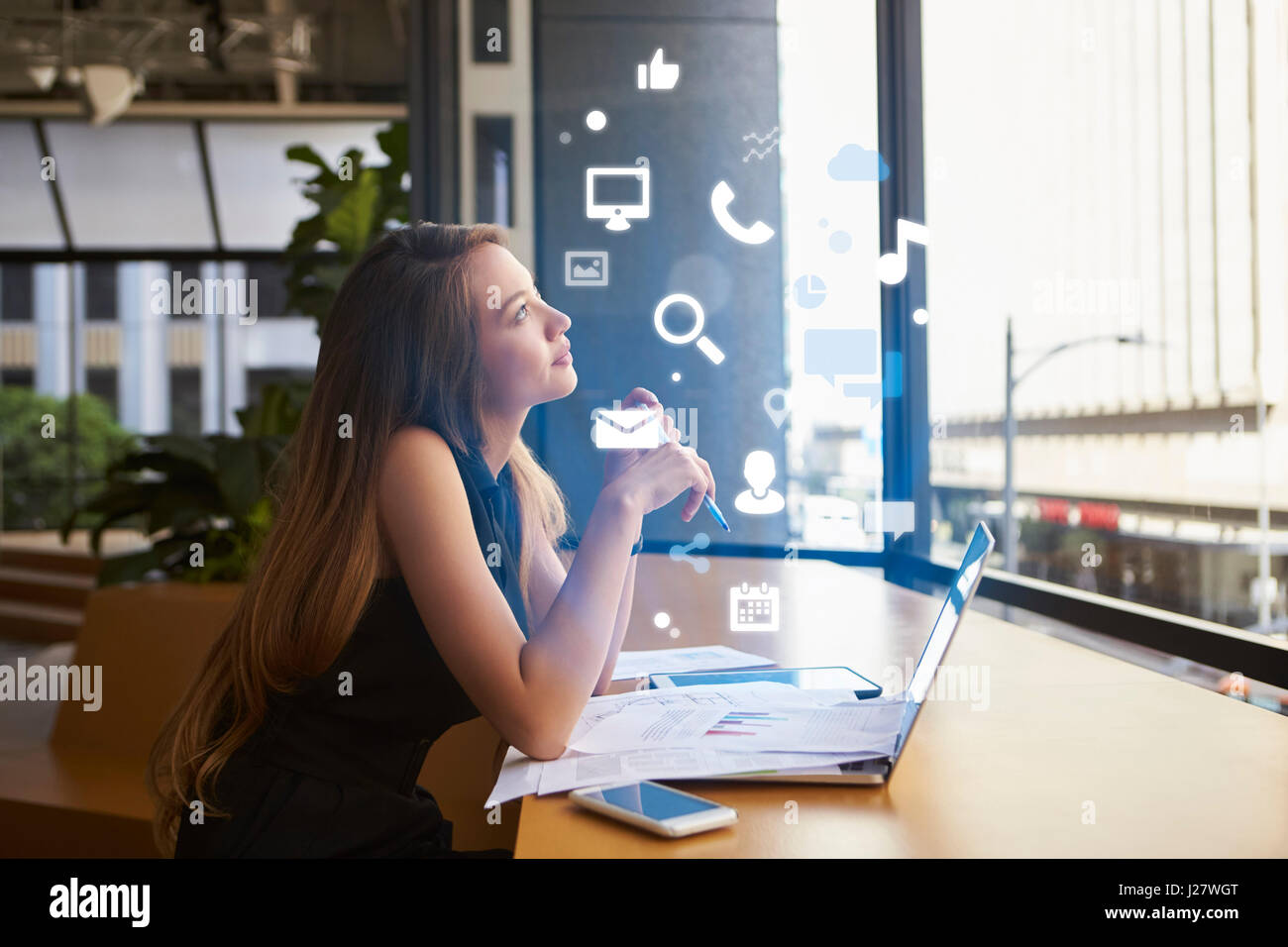 Businesswoman working in an office looking at app icons Stock Photo - Alamy
