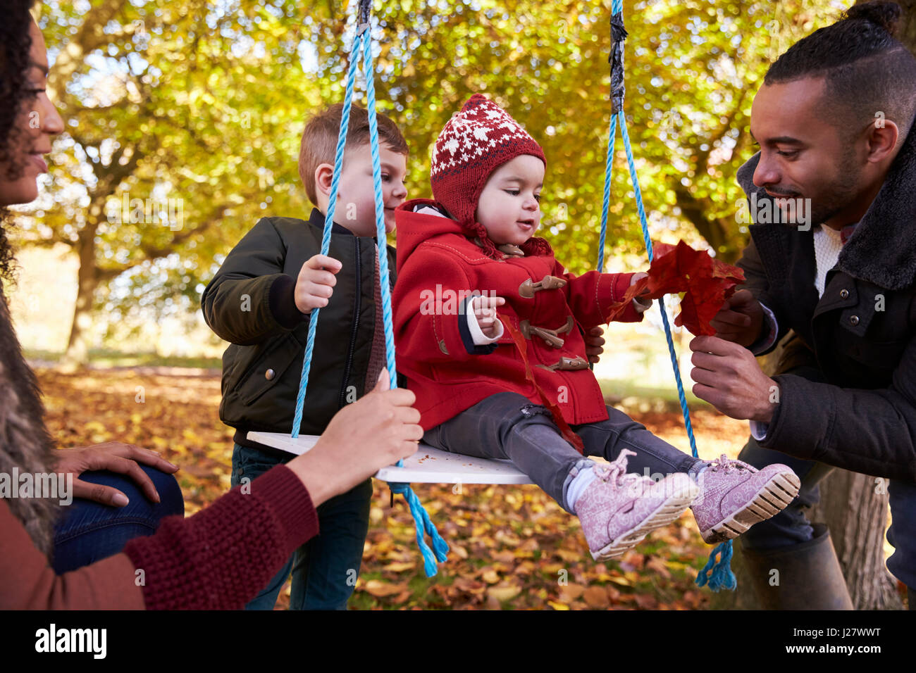 Parents With Children Playing On Tree Swing In Autumn Garden Stock ...