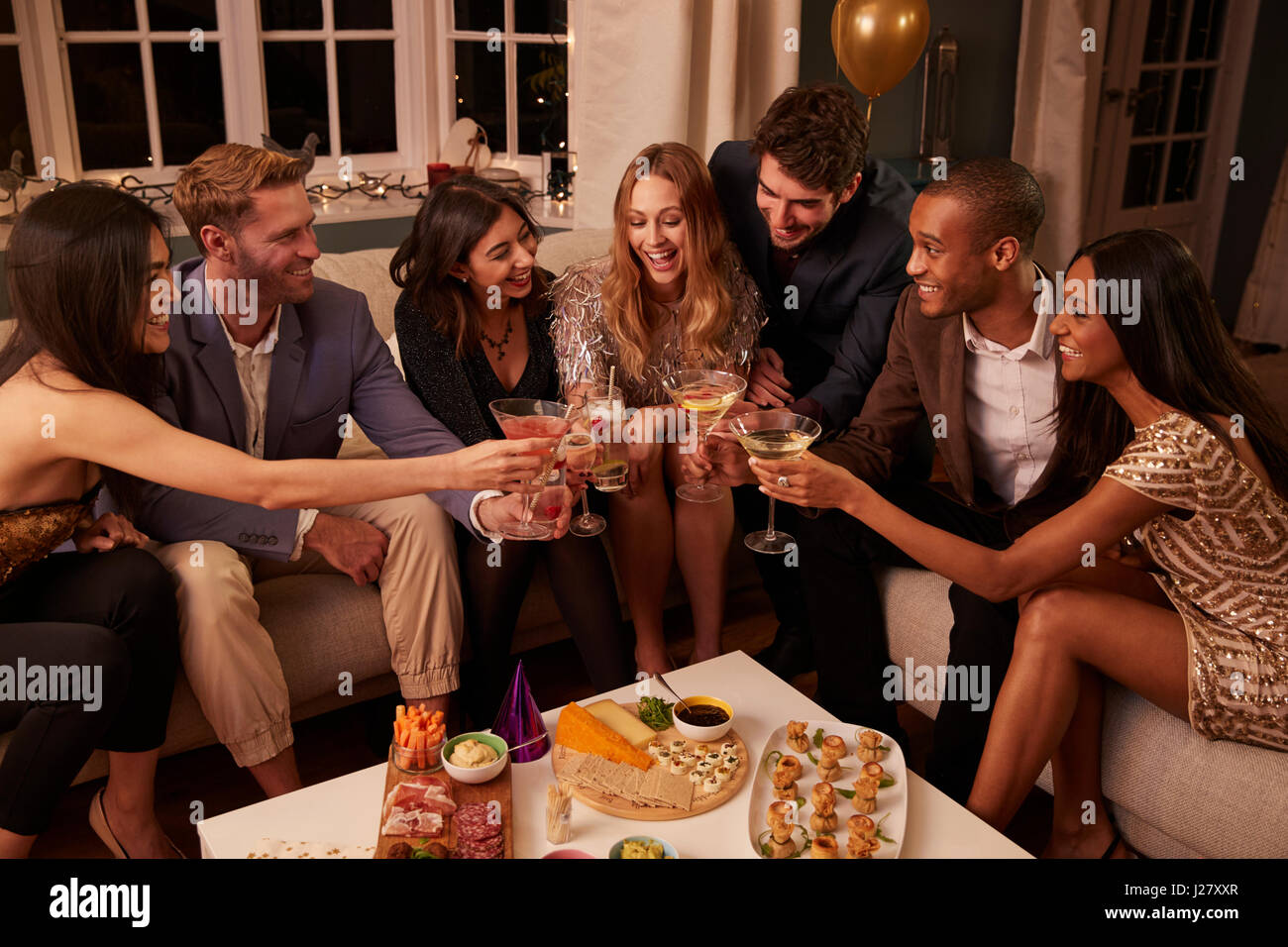 Friends Eating Snacks As They Celebrate At Party Together Stock Photo ...