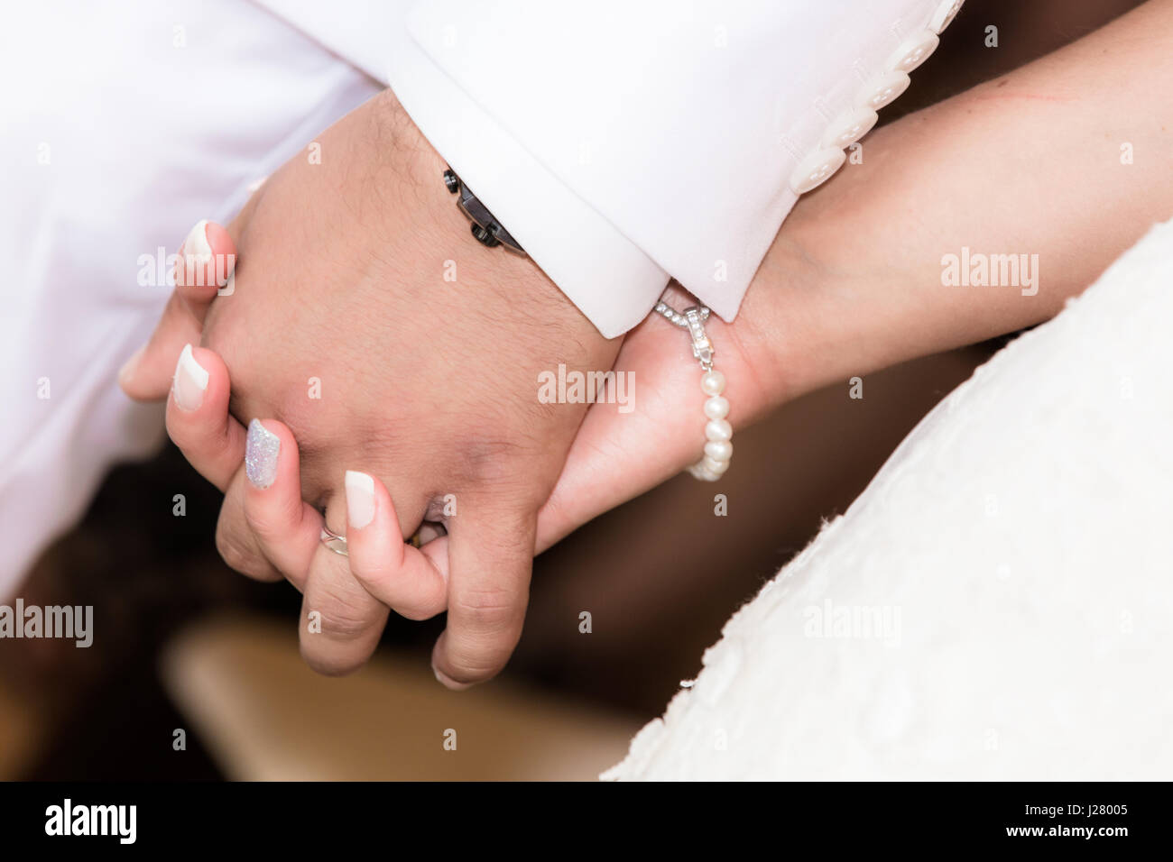 Close up of bride and groom holding hands during the marriage ceremony ...